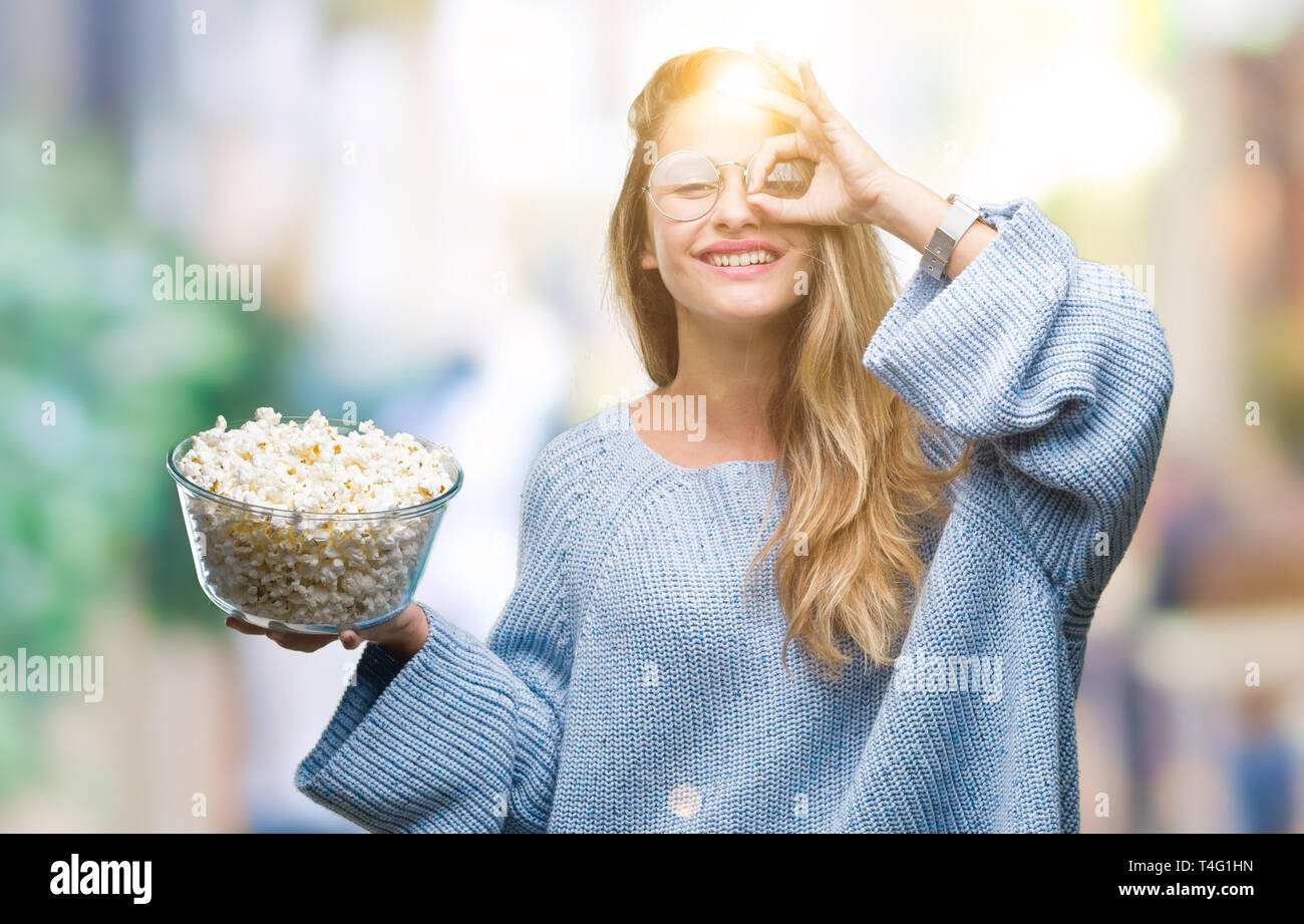 Young beautiful blonde woman eating popcorn over isolated background ...