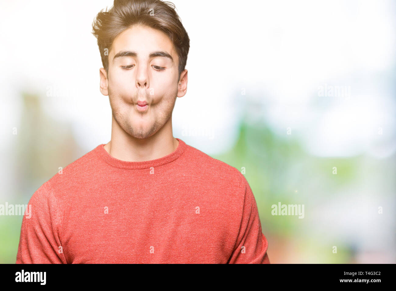 Young handsome man over isolated background making fish face with lips ...