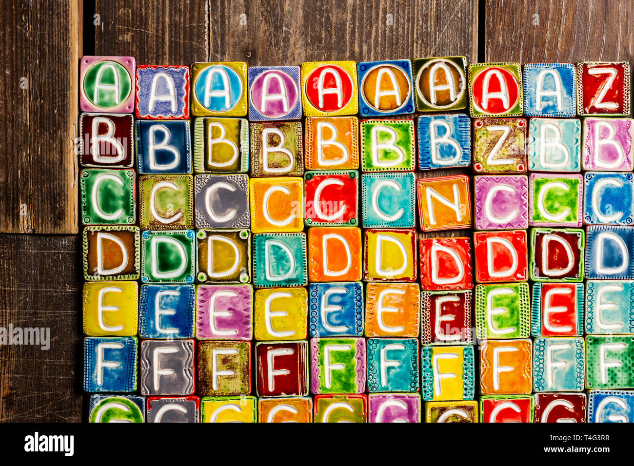 Colorful handmade ceramic alphabet on wood texture Stock Photo - Alamy