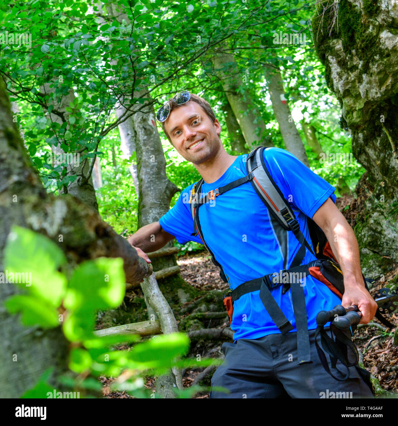 Young man hiking in forest with smiling face Stock Photo - Alamy