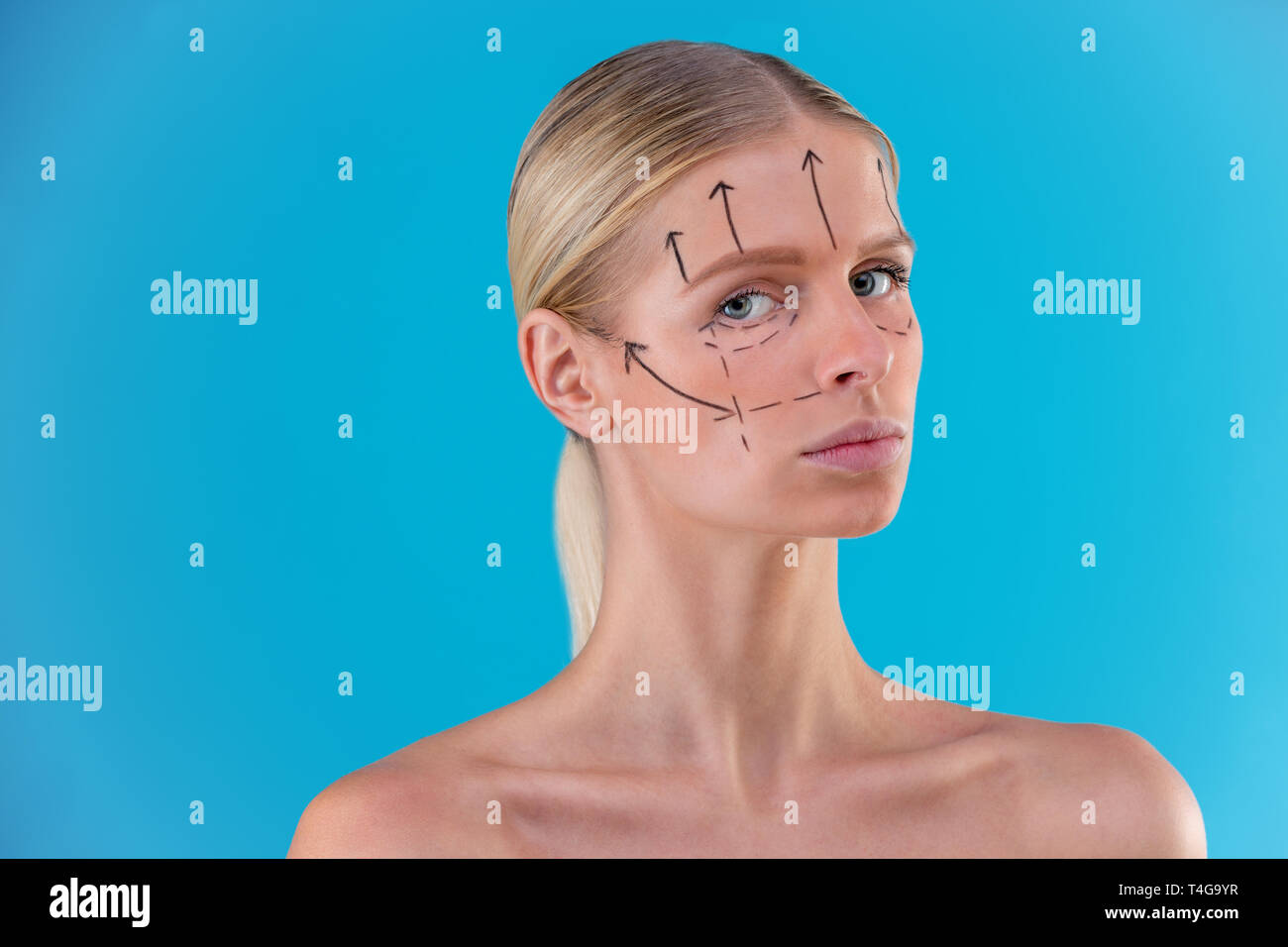 Beautician draw correction lines on woman face. Before plastic surgery ...