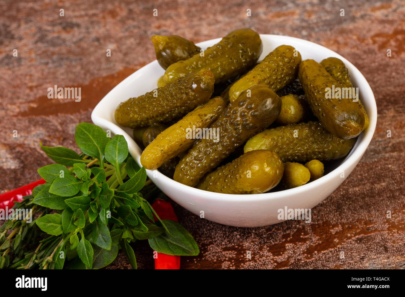 Pickled small cucumbers in the bowl served herbs Stock Photo - Alamy