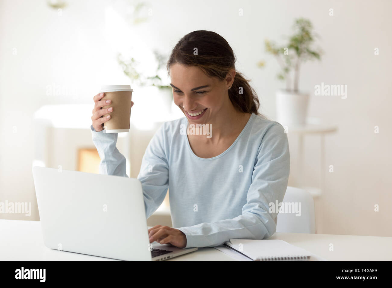 Woman at work typing message on laptop smiling Stock Photo - Alamy