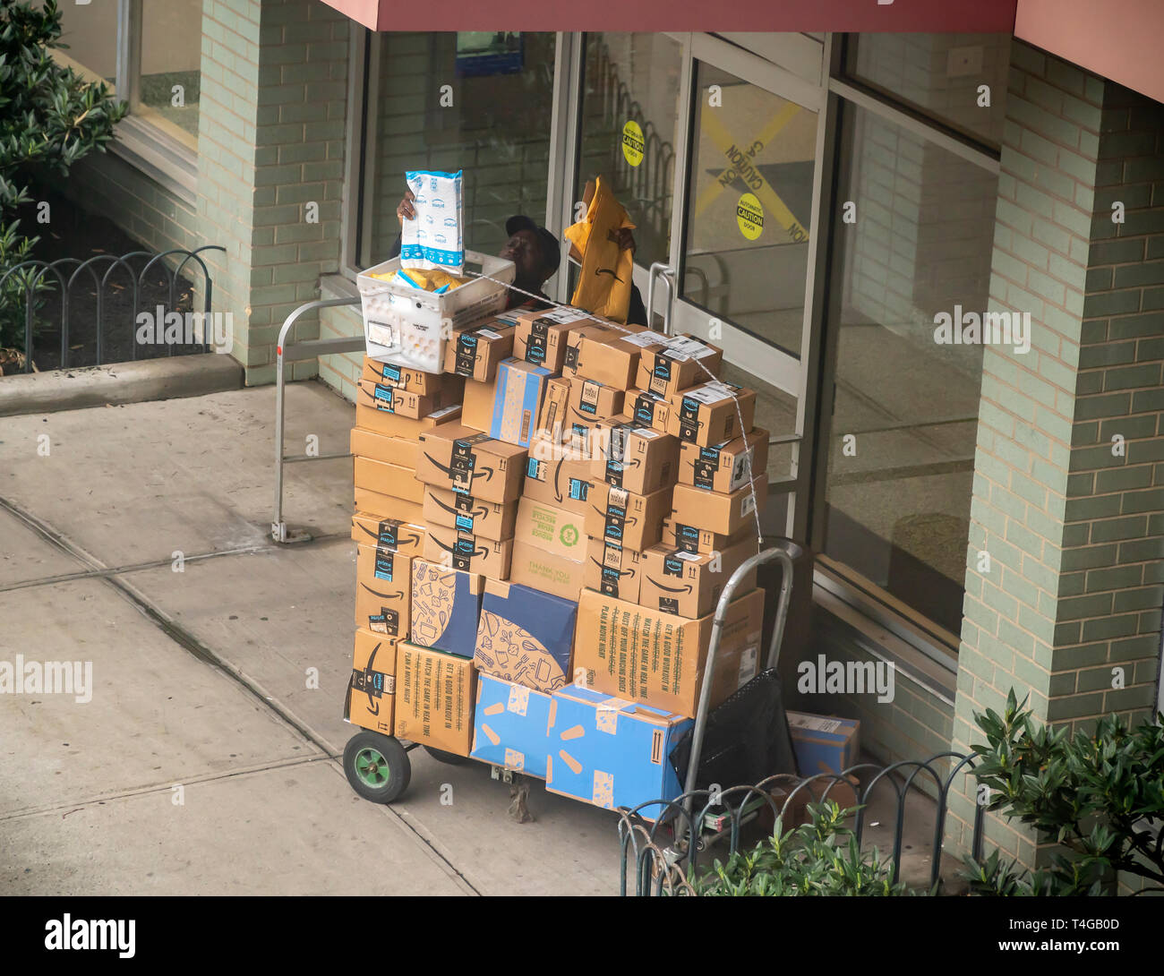 A deliveryman with his cart laden with purchases, mostly Amazon ...