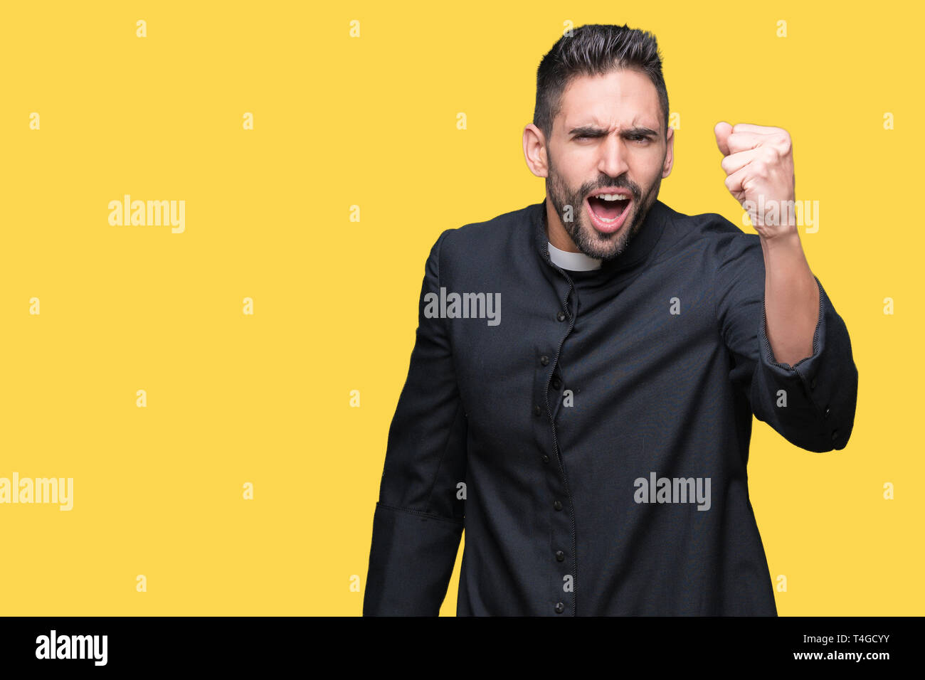 Young Christian priest over isolated background angry and mad raising ...