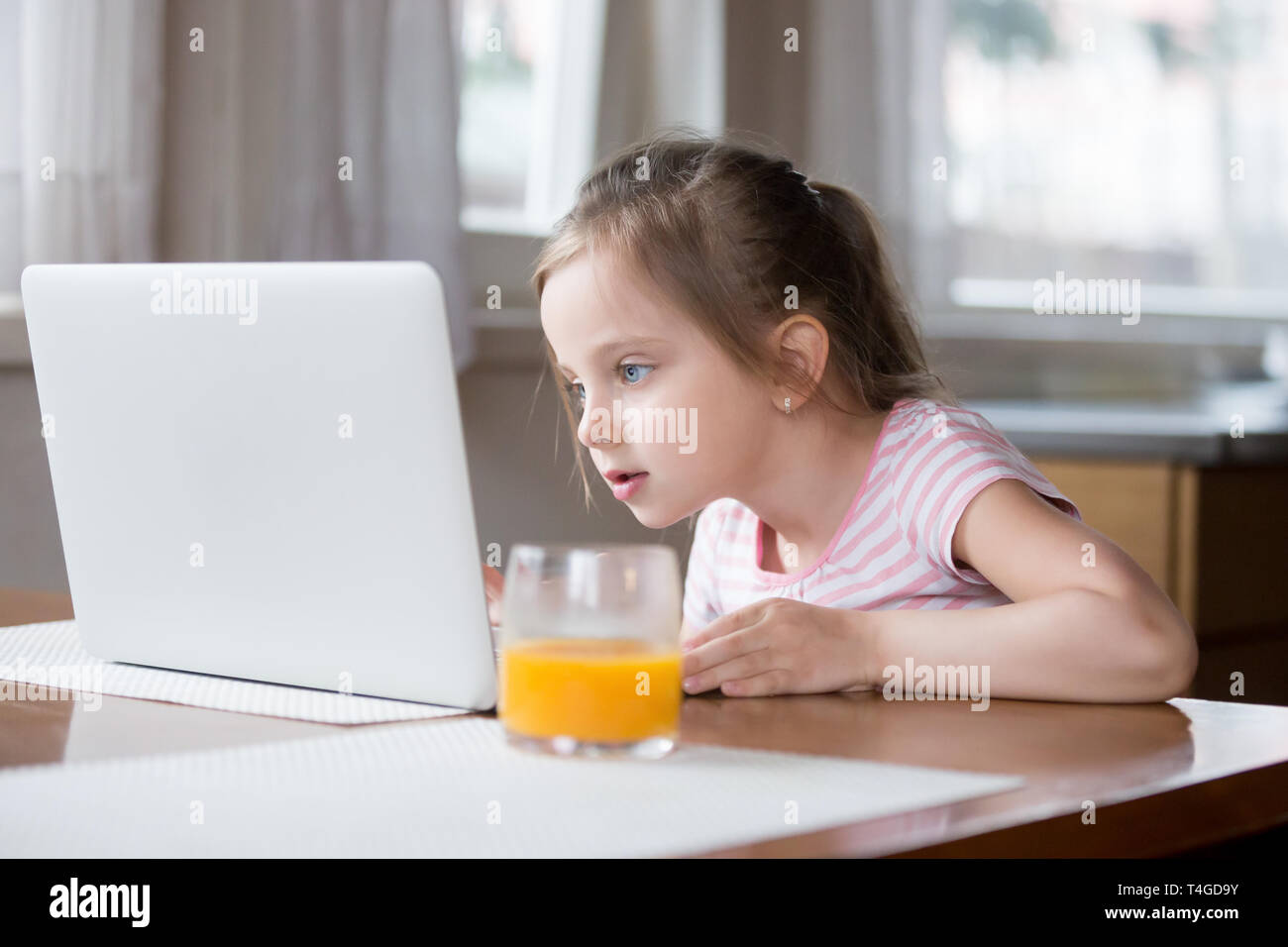Little girl busy playing computer in kitchen at home Stock Photo - Alamy