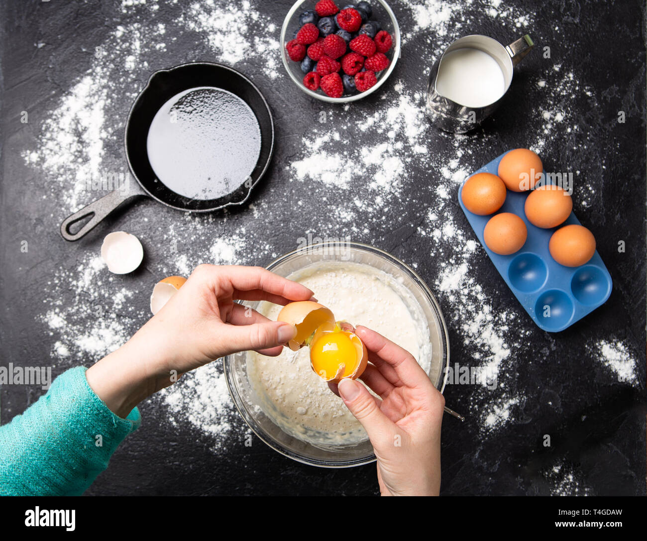 Photo of hands of man breaking eggs in bowl. Table with berries, milk ...