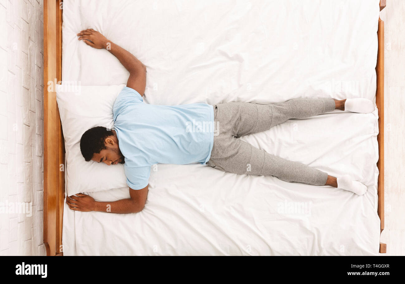 Young african-american man sleeping in bed top view Stock Photo - Alamy