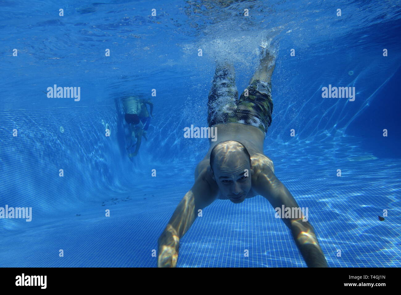 Man swimming underwater in a swimming pool, facing the cam Stock Photo ...