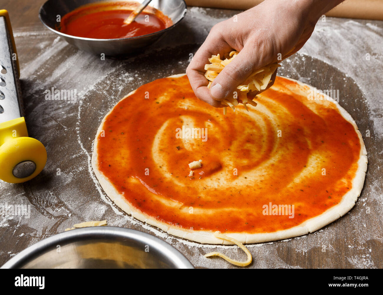 Process of preparing pizza. Man adding cheese on base Stock Photo - Alamy