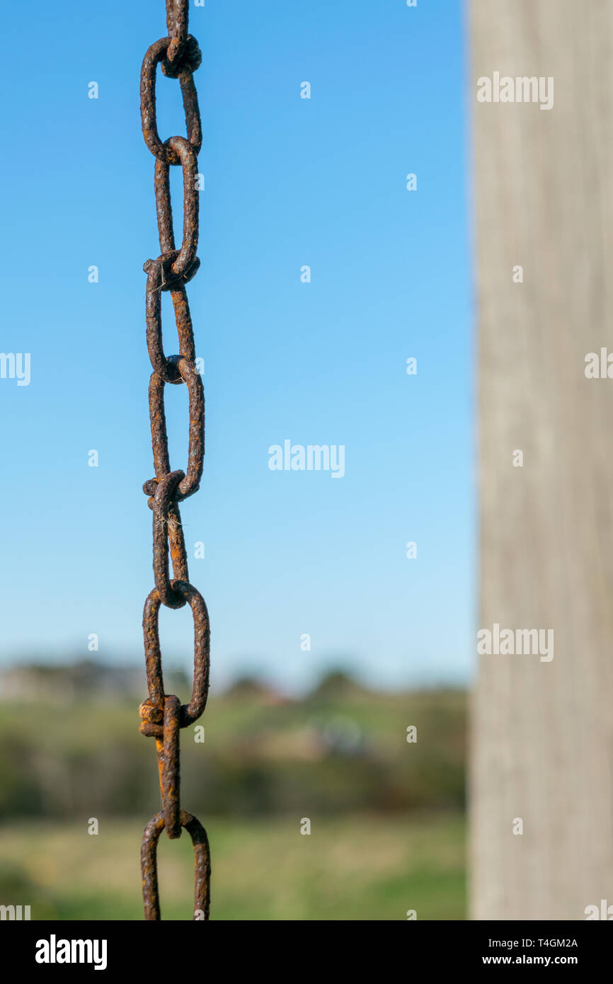 Old rusty chain and chain links against a natural blue sky and green ...