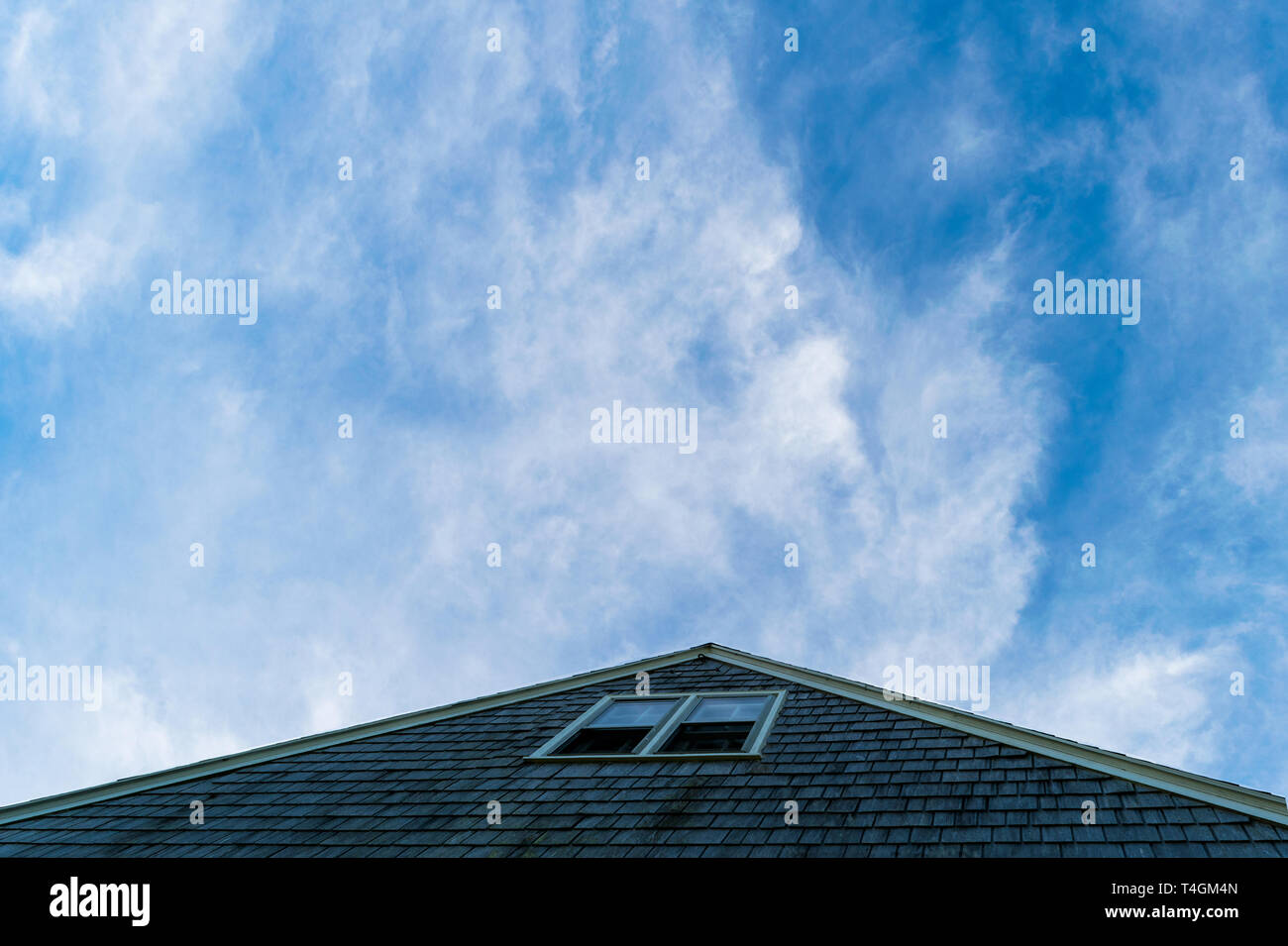 Triangular rooftop pointing toward a beautiful blue slightly cloudy sky ...