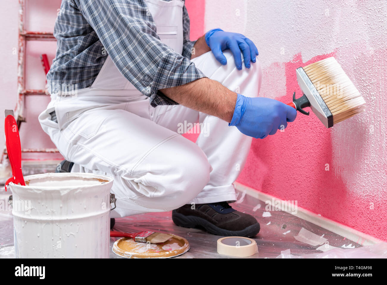 Caucasian house painter worker in white overalls, with the brush ...