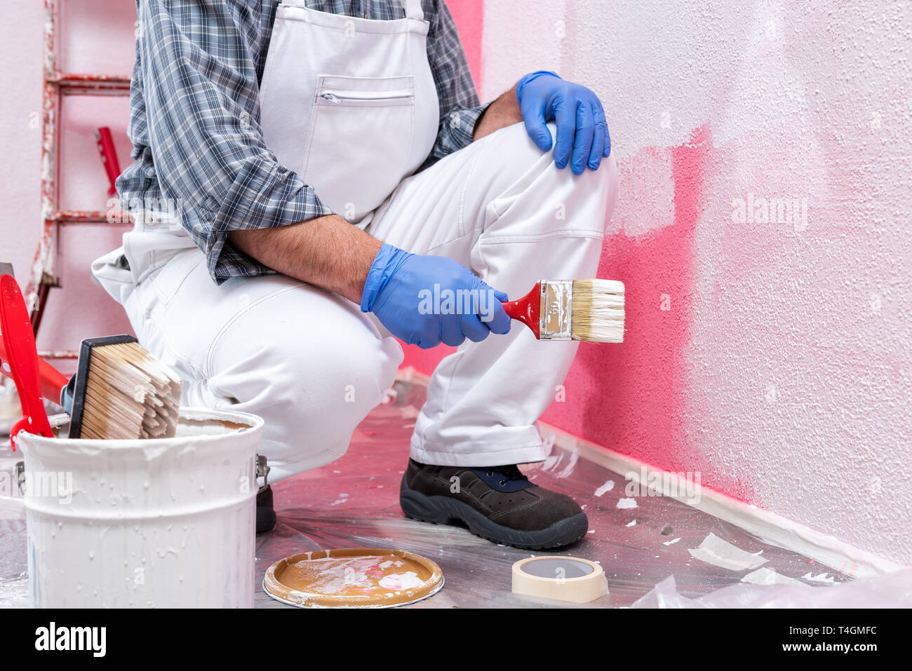 Caucasian house painter worker in white overalls, painting the pink ...