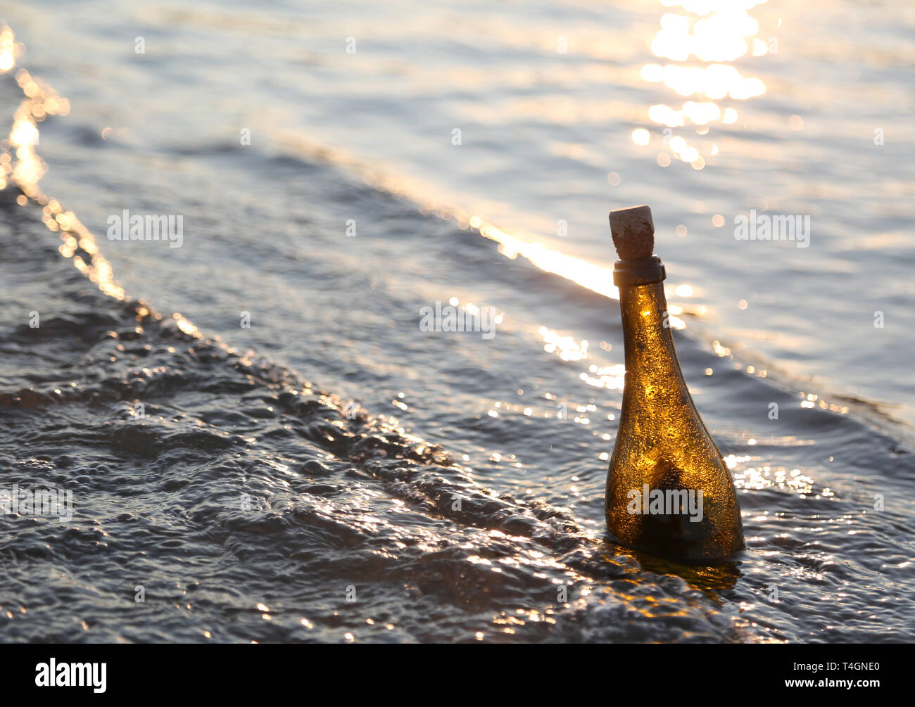 glass bottle containing a treasure map floating on the sea at sunset ...