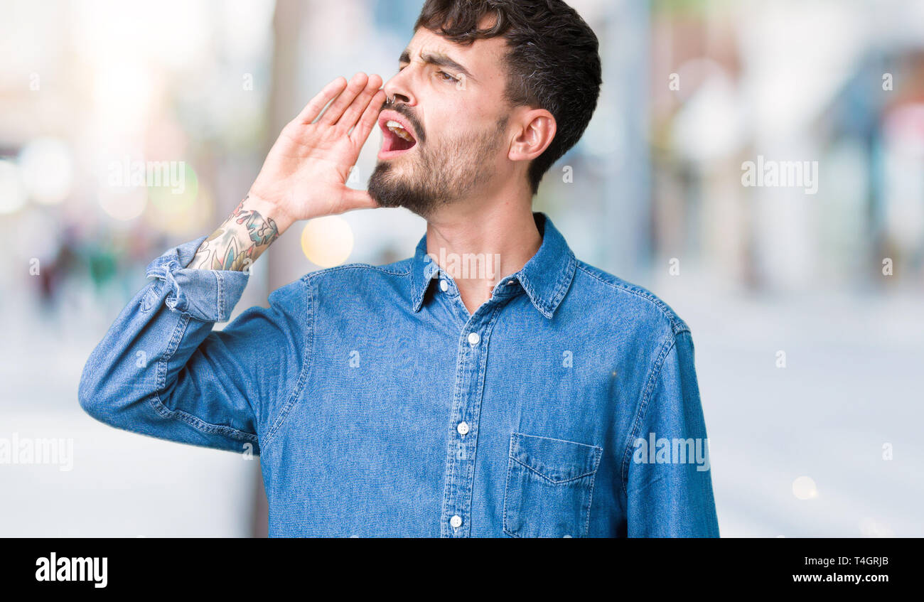 Young handsome man over isolated background shouting and screaming loud ...