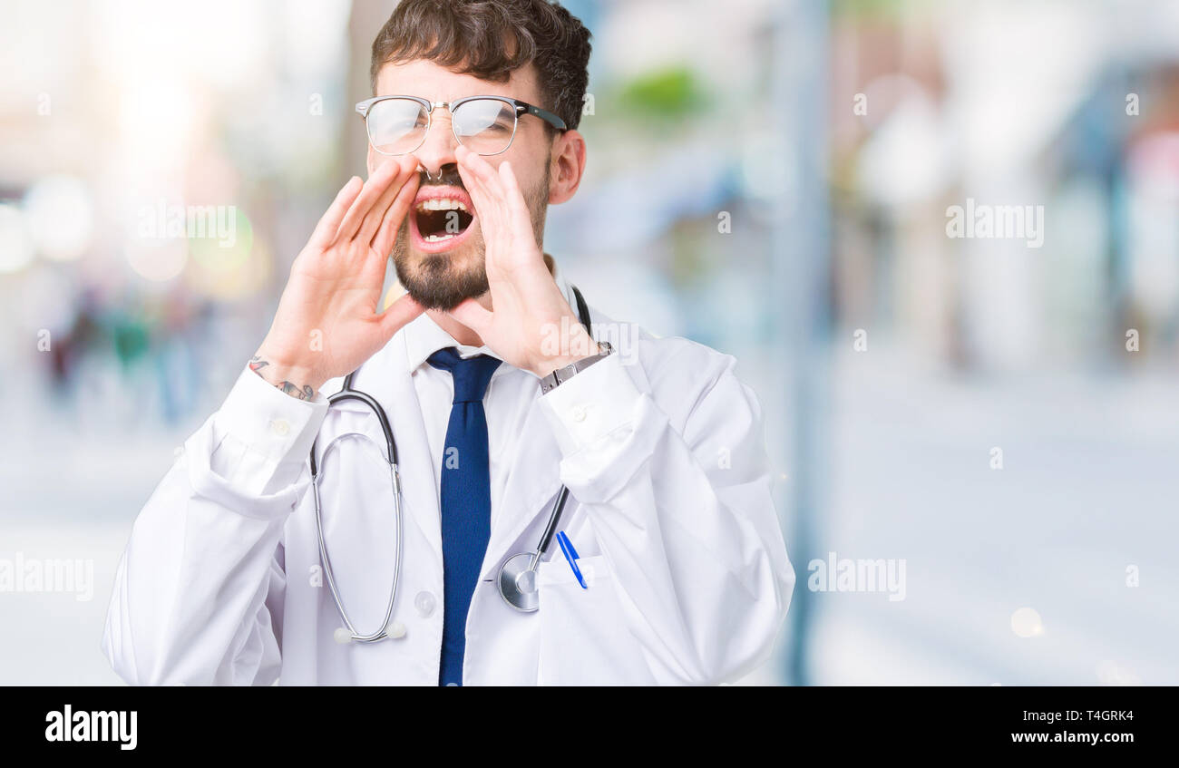 Young doctor man wearing hospital coat over isolated background ...