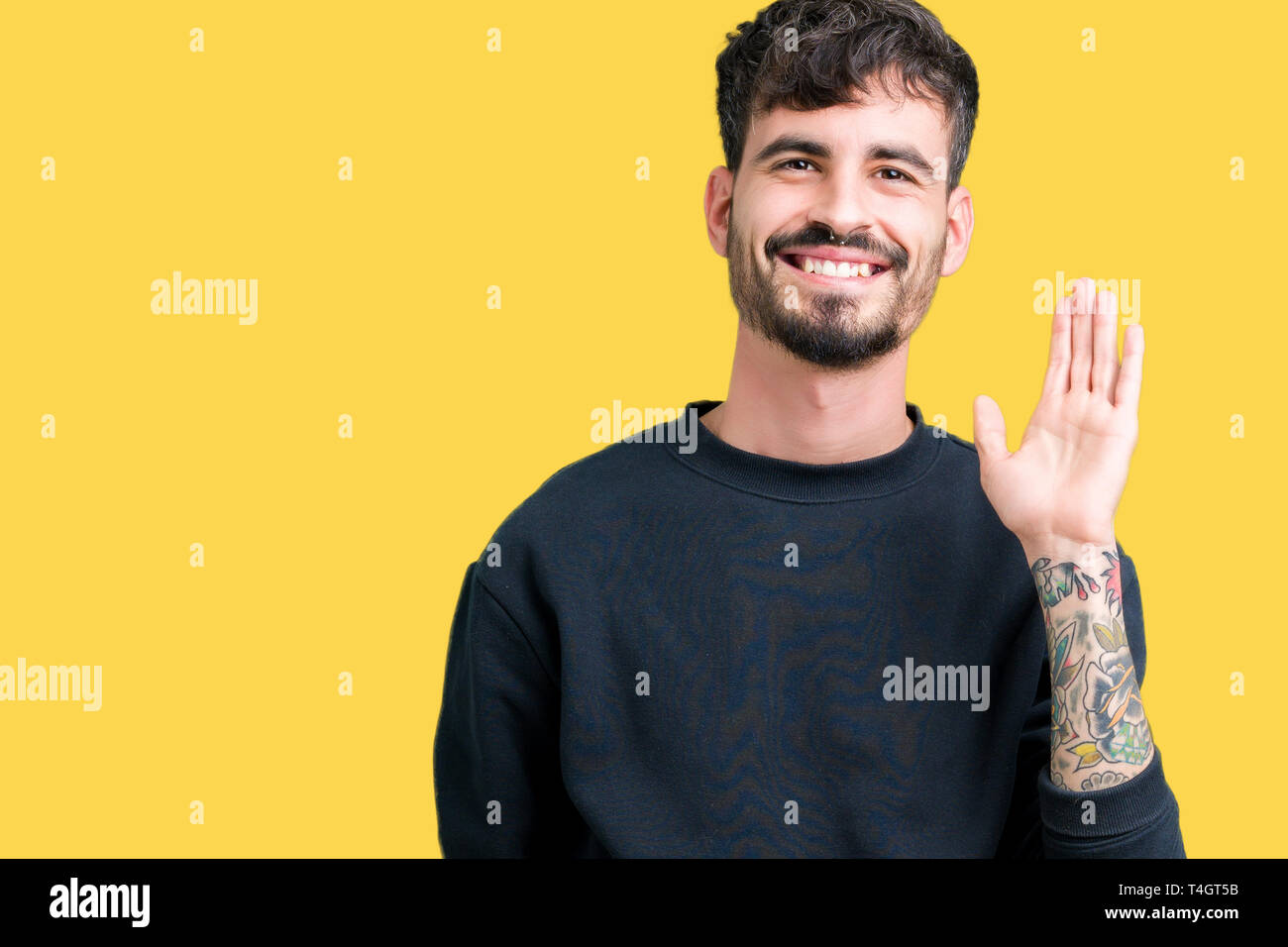 Young handsome man over isolated background Waiving saying hello happy ...