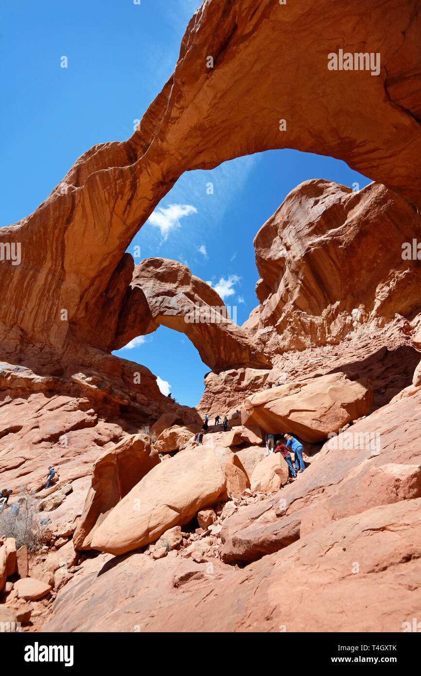 Visitors hike the sandy trail to ascend the awe inspiring Double Arch ...