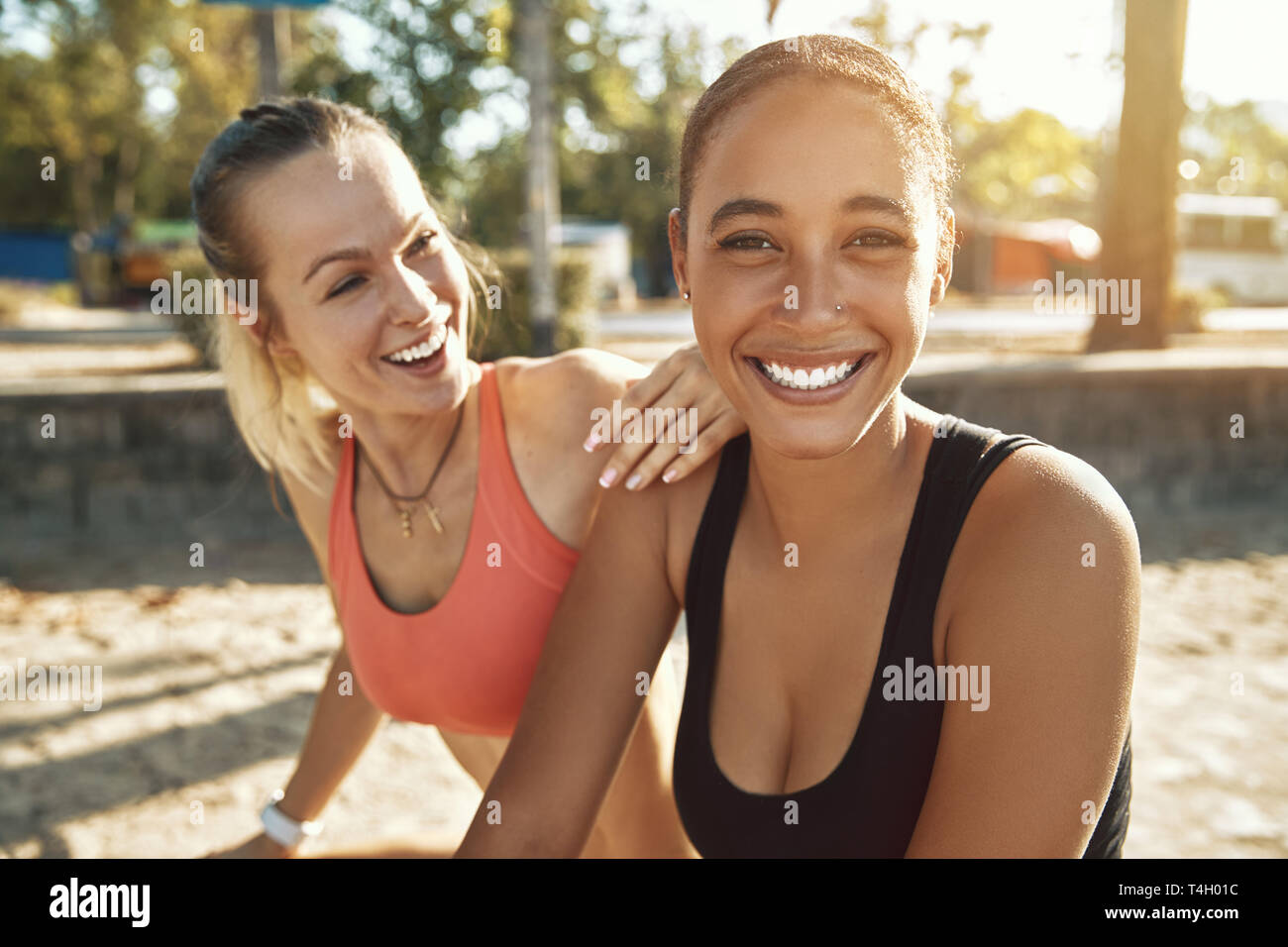 Smiling young women in sportswear sitting with her exercise partner ...