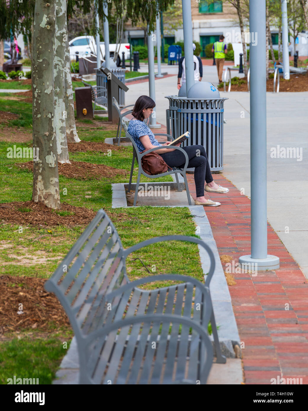 ASHEVILLE, NC, USA-4/11/19: A young woman, sitting on park bench in ...