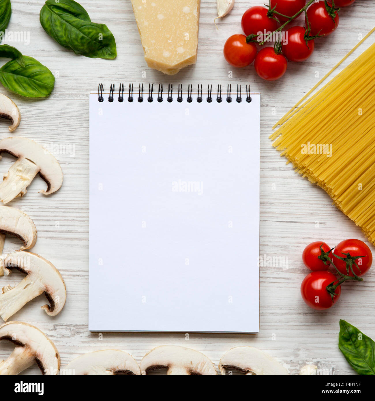 Notepad with ingredients for cooking pasta on a white wooden surface ...