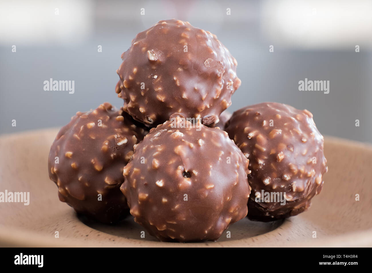 Four Round Chocolate and Crushed Almond Crispy Balls on a small serving ...