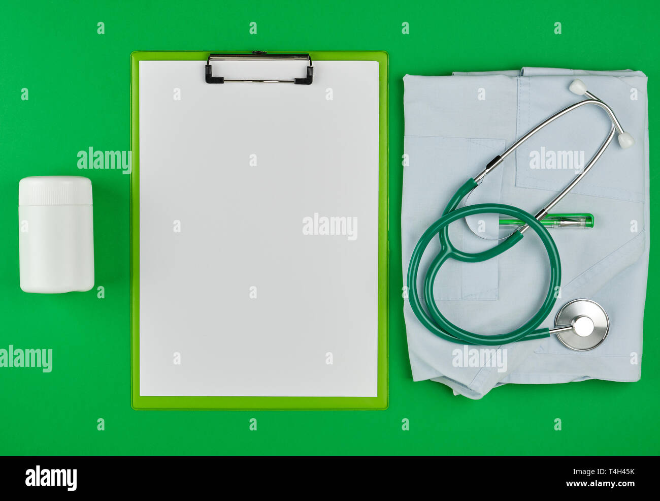 paper holder with empty white sheets, medical stethoscope, pills on a ...
