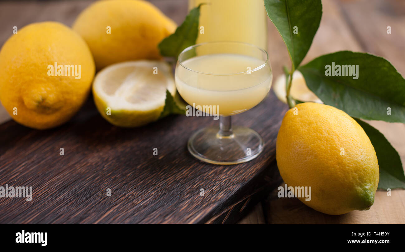limoncello in a glass and fresh citrus fruits with green leaves ...