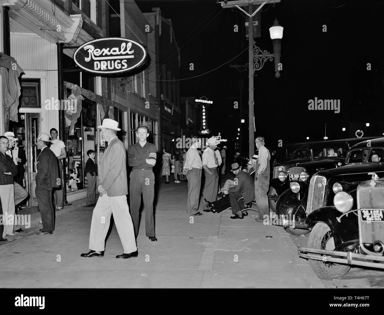 A 1940s sidewalk with a drug store and vehicles Stock Photo - Alamy