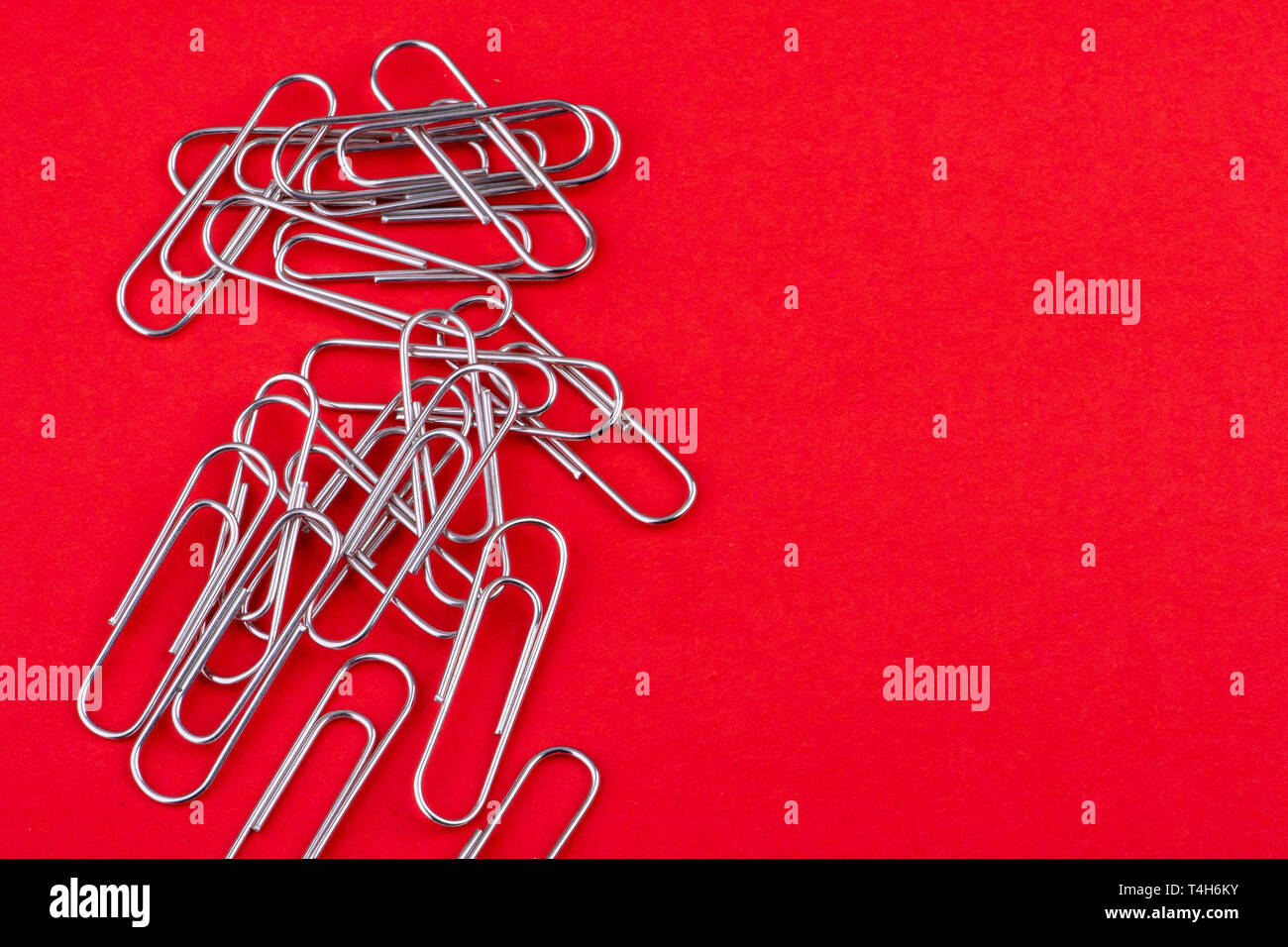 Paperclips mixed up on a red background Stock Photo - Alamy
