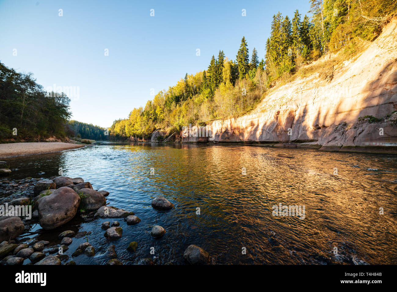 beautiful golden sunrise over forest river with sandstone cliffs on the ...