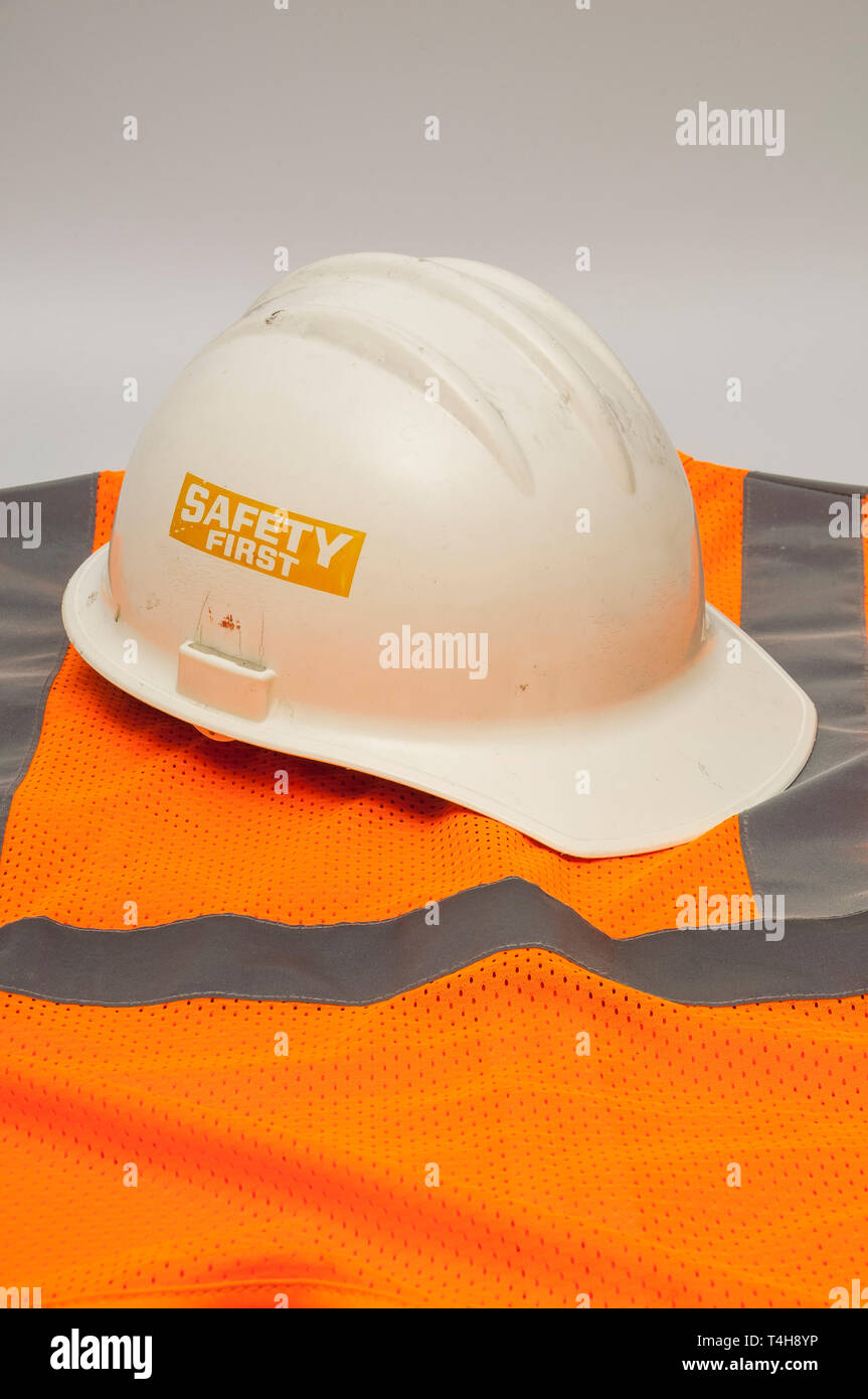 Two hard hats and an orange vest Stock Photo - Alamy
