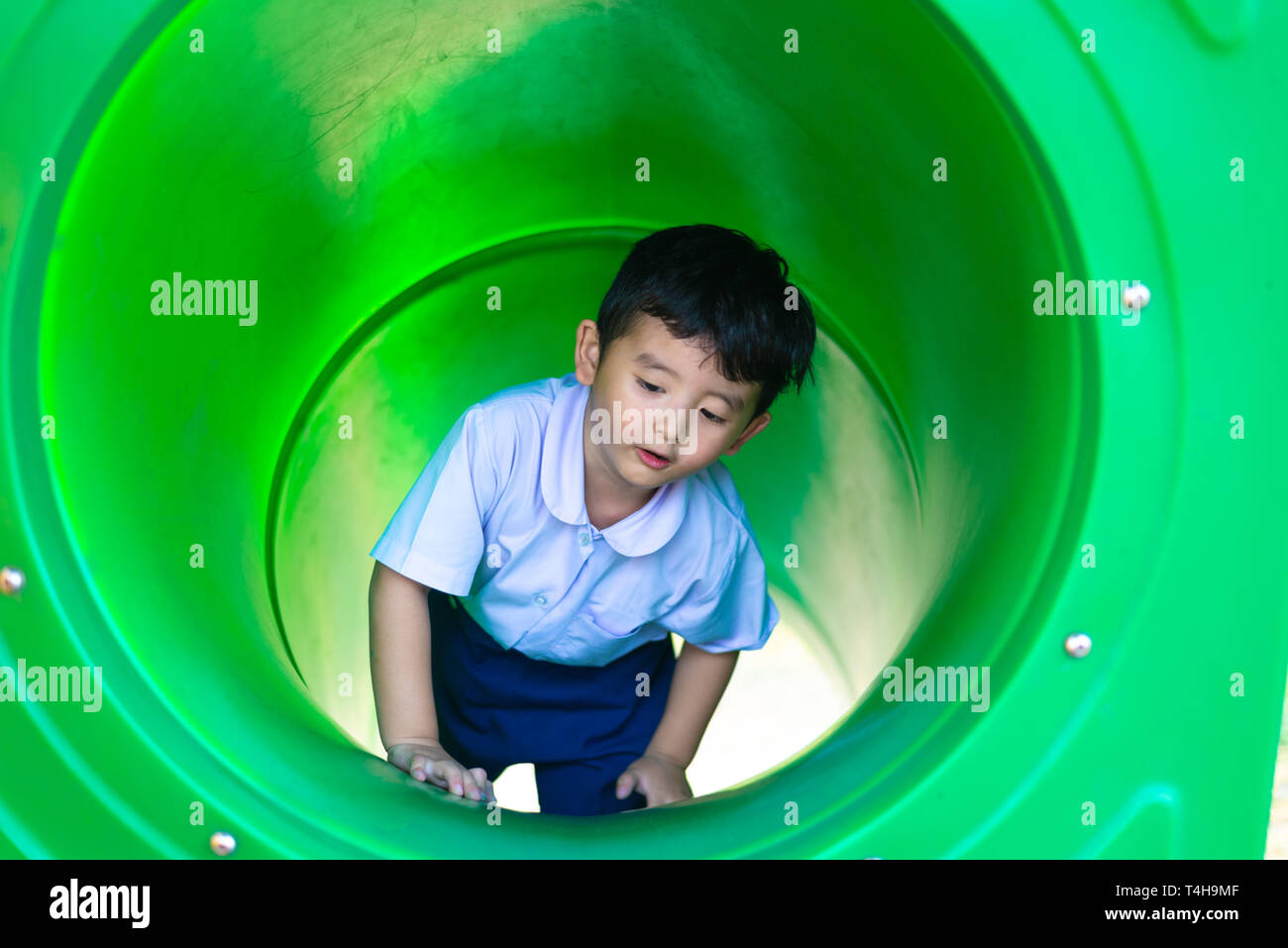 Little Asian kid climbing up the slide at the playground under the ...