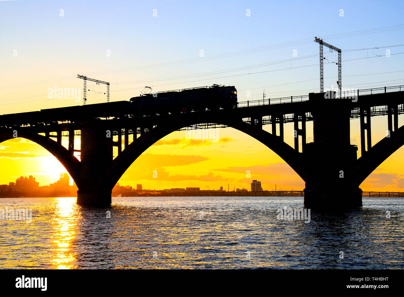 Silhouette of arched railway bridge and a train at beautiful sunset ...