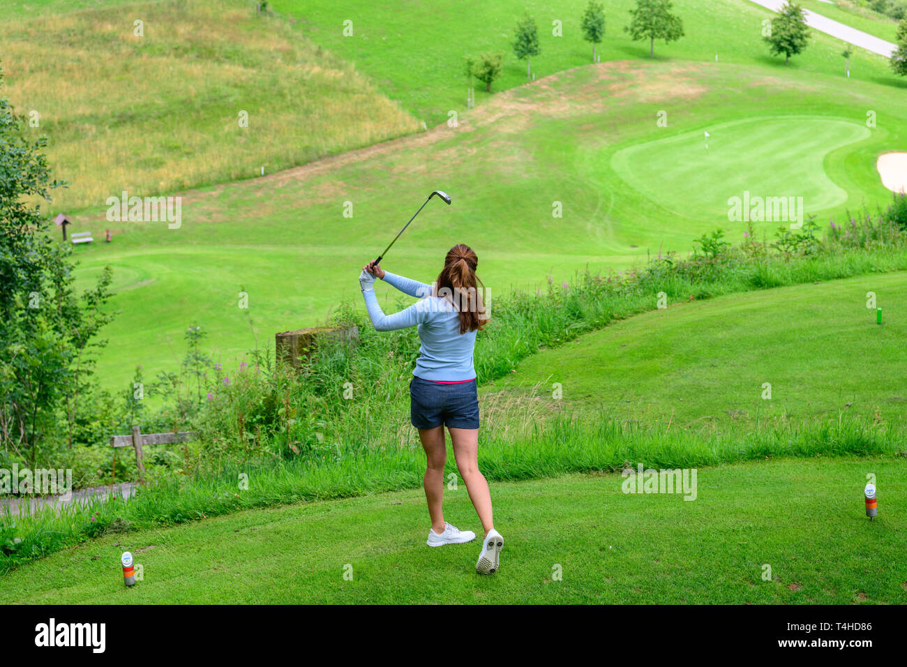 Female golf player hitting ball from tee Stock Photo - Alamy