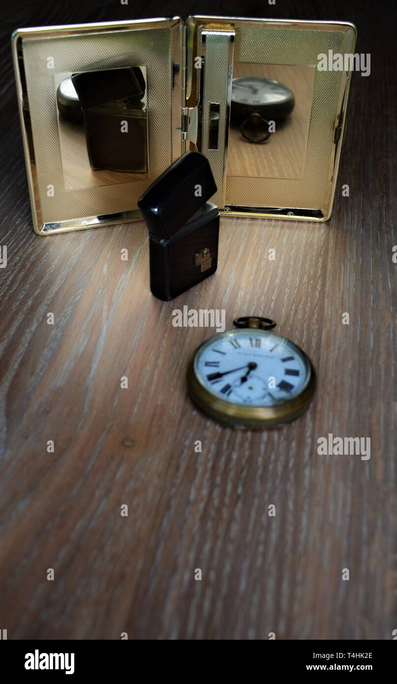 Pocket watch, lighter and cigarette case still life. Reflections from ...