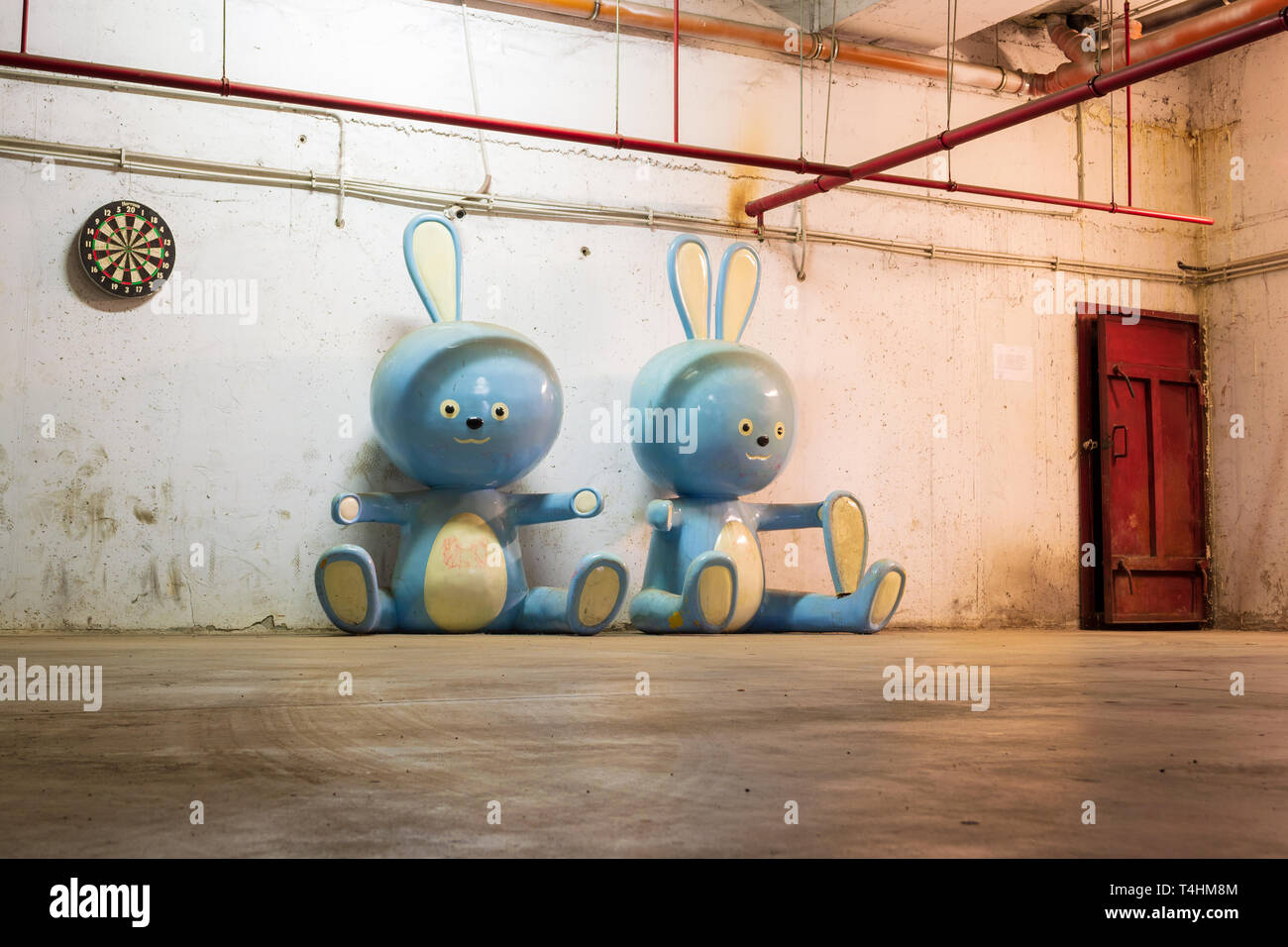 Two giant rabbit figurines near a rusty door, in a basement. One rabbit ...