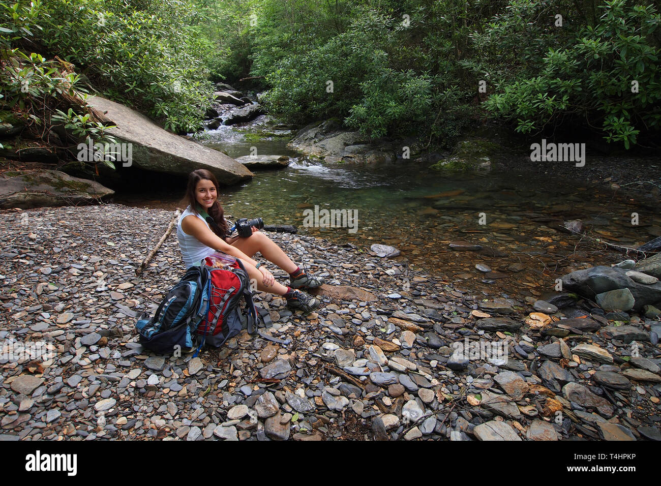 A young woman sitting by a trailside stream in the Great Smoky ...