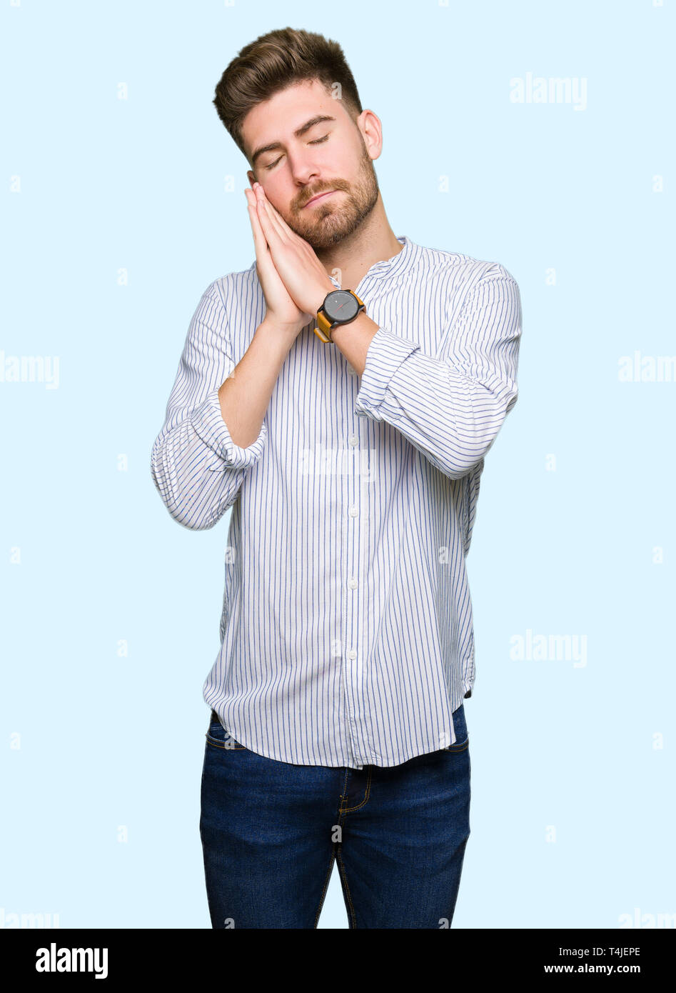 Young handsome man sleeping tired dreaming and posing with hands ...