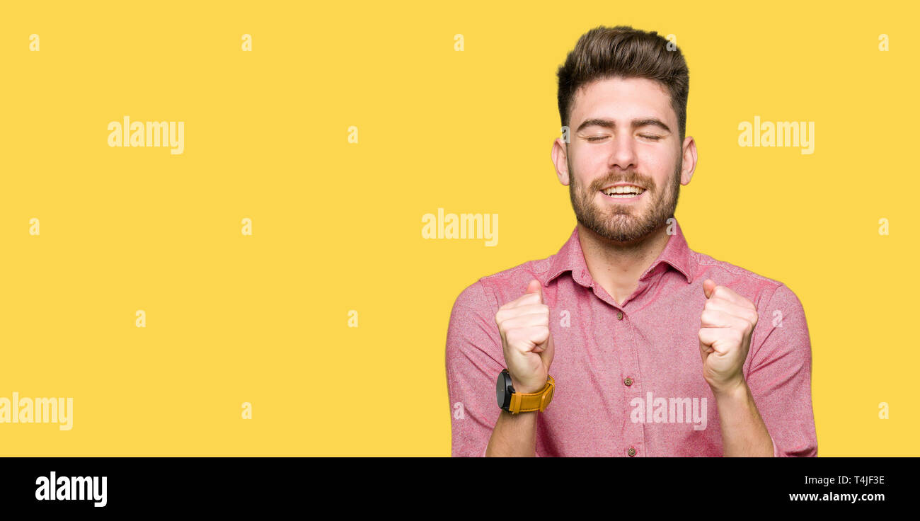 Young handsome business casual man excited for success with arms raised ...