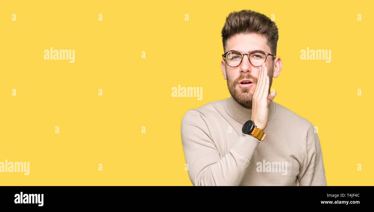 Young handsome business man wearing glasses hand on mouth telling ...
