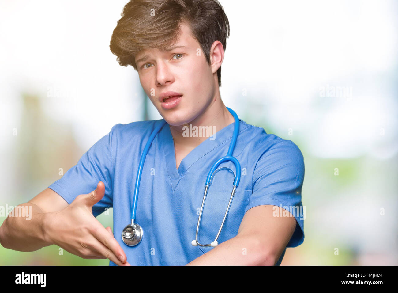 Young doctor wearing medical uniform over isolated background In hurry ...
