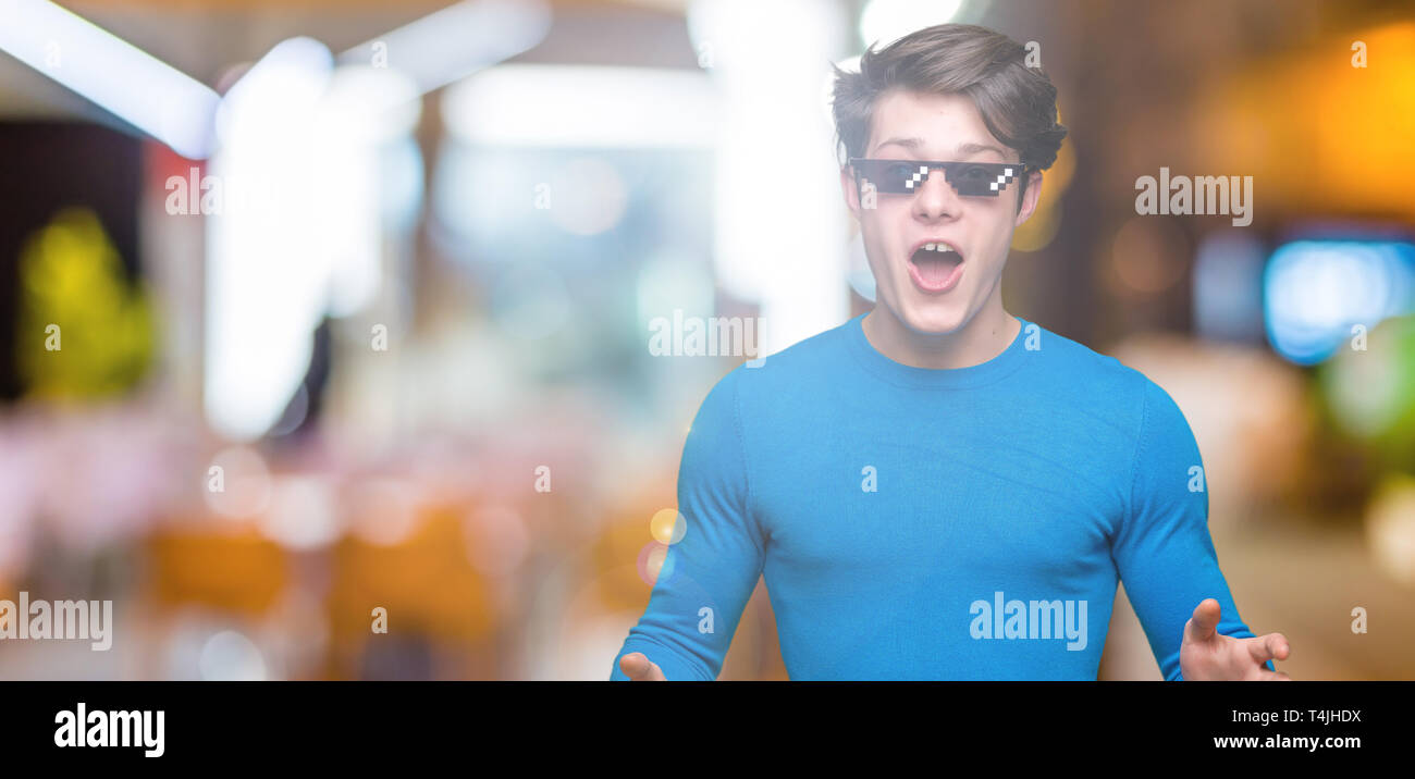 Young man wearing funny thug life glasses over isolated background ...