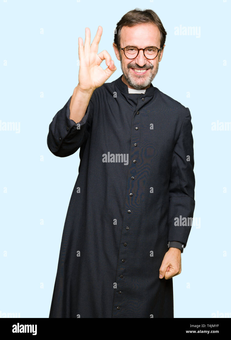 Middle age priest man wearing catholic robe smiling positive doing ok ...