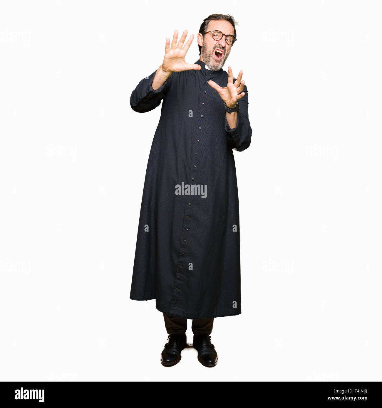 Middle age priest man wearing catholic robe afraid and terrified with ...