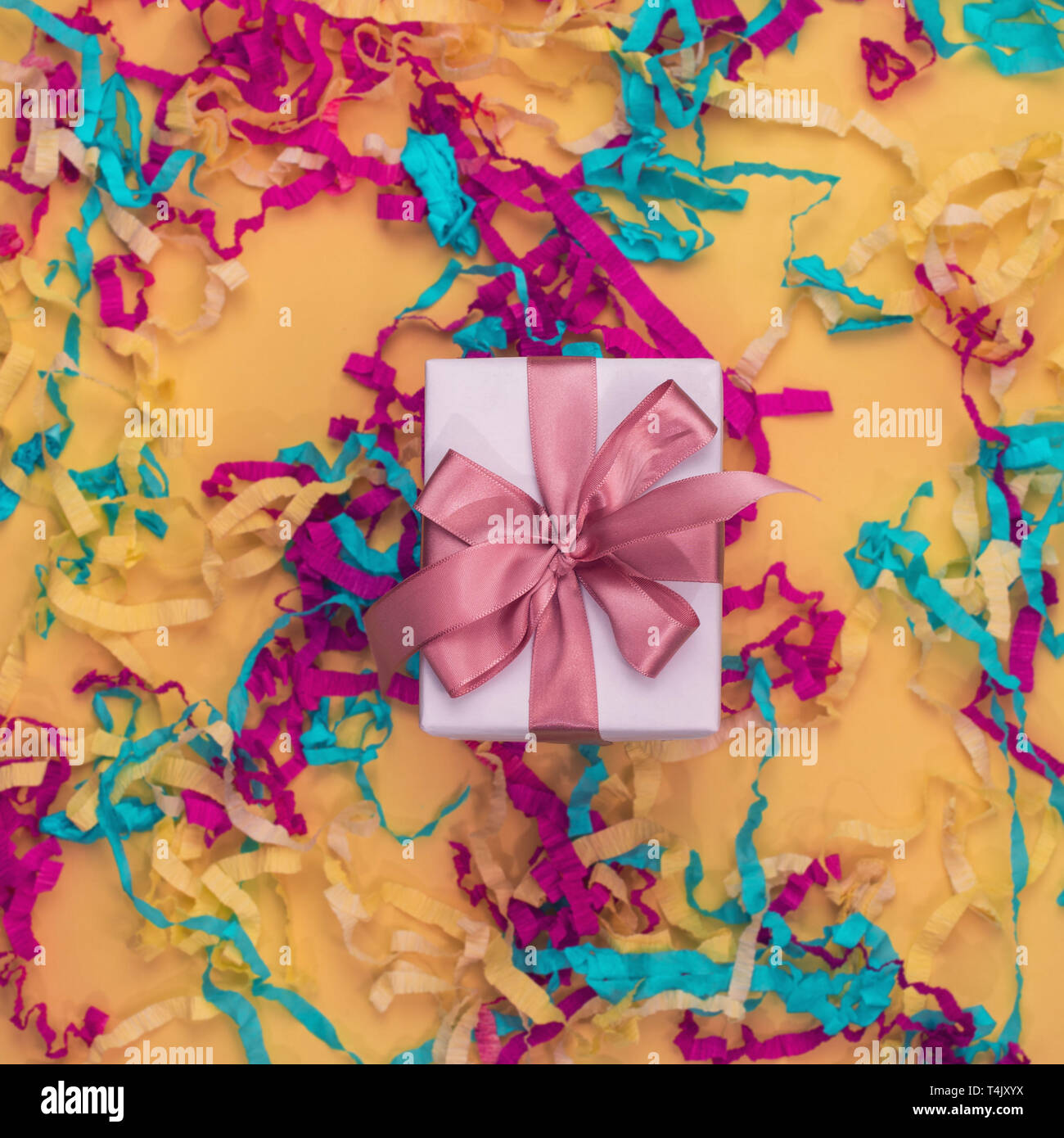 Gift box with colored streamers bright yellow background. A top view of ...