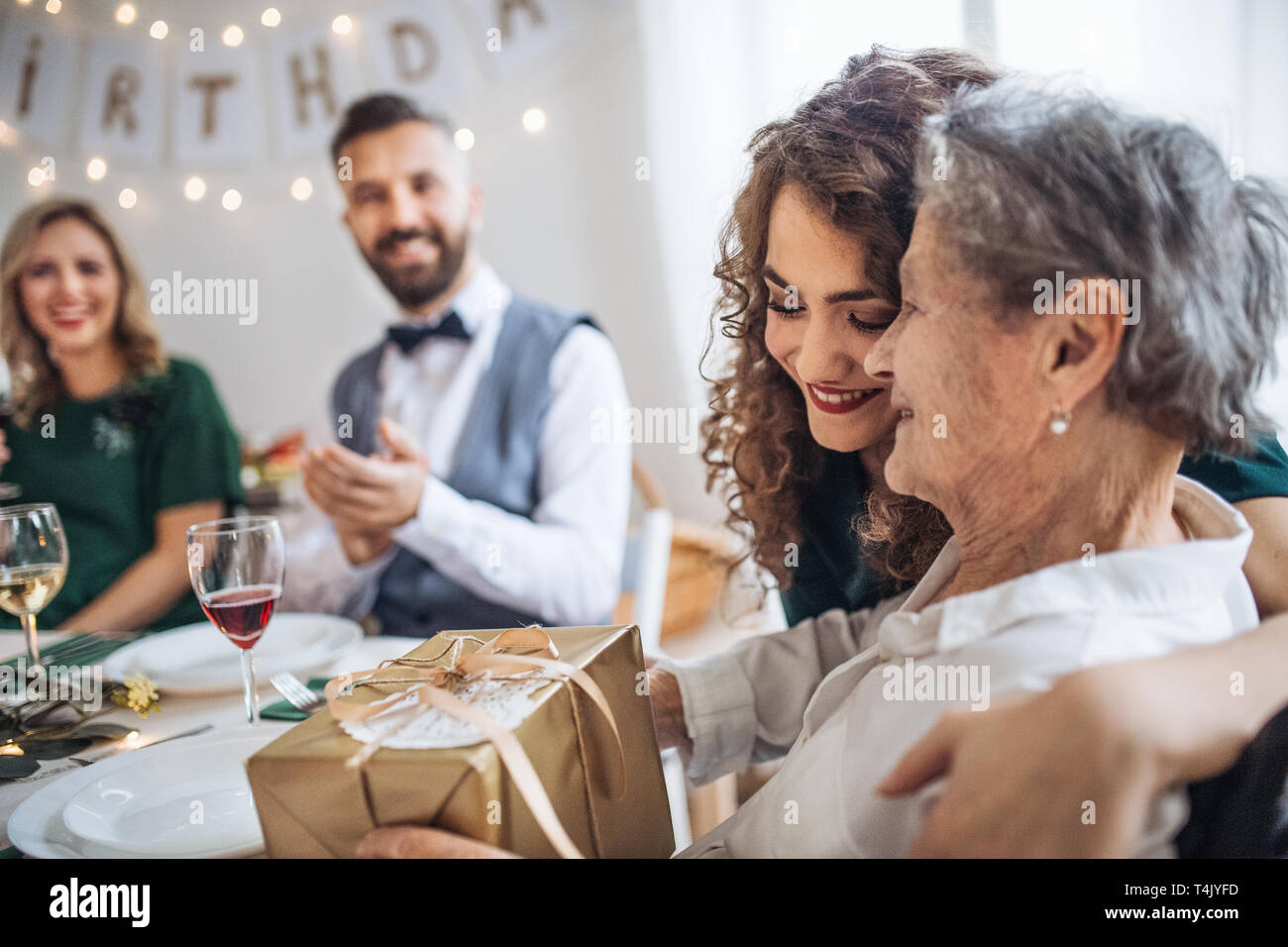An elderly grandmother celebrating birthday with family and receiving a ...