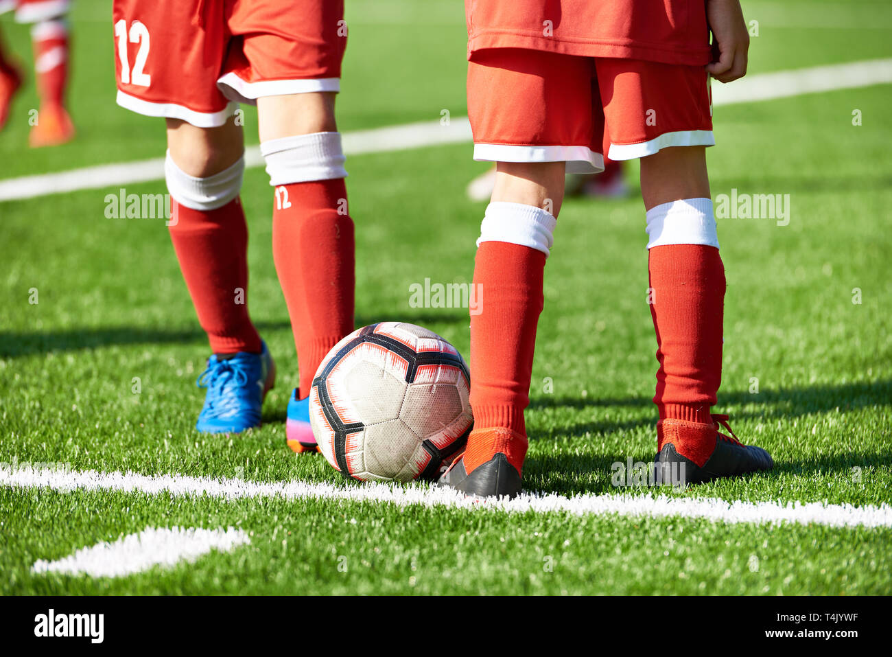 Boys soccer players in red sports uniform with a ball on the football ...