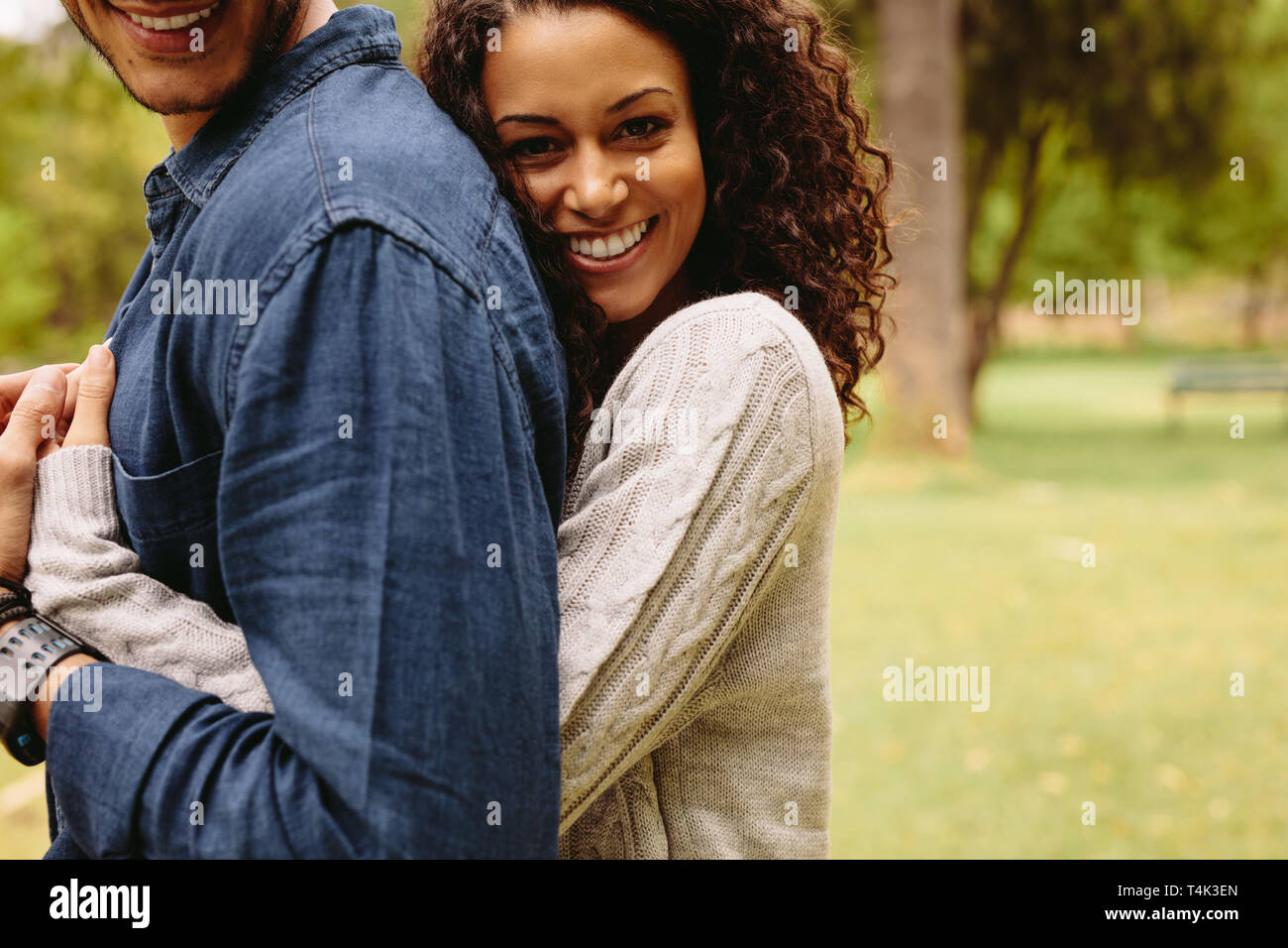 Beautiful woman hugging her boyfriend from behind and smiling. Loving couple at park Stock Photo ...